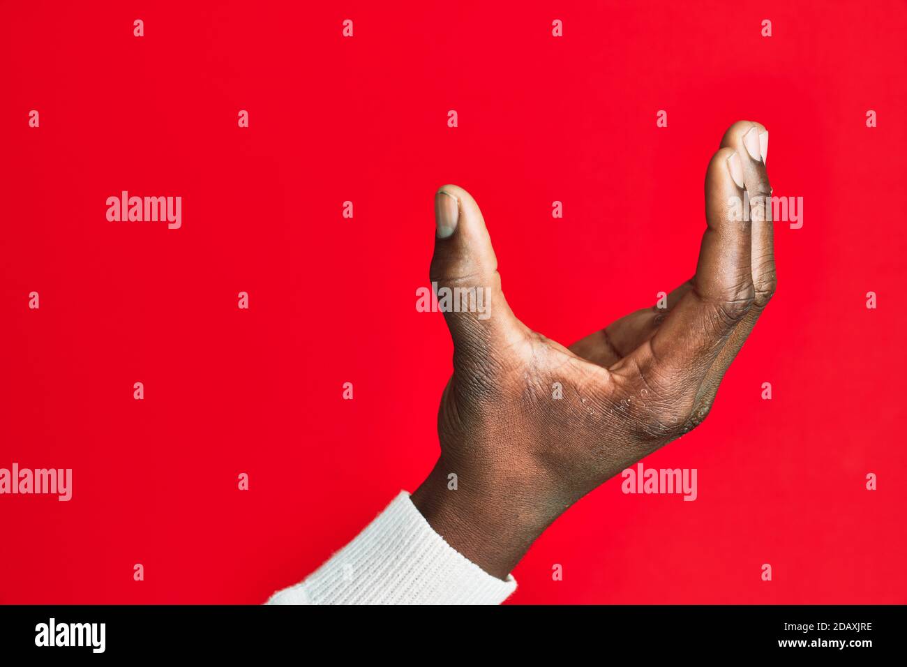 Arm and hand of african american black young man over red isolated ...