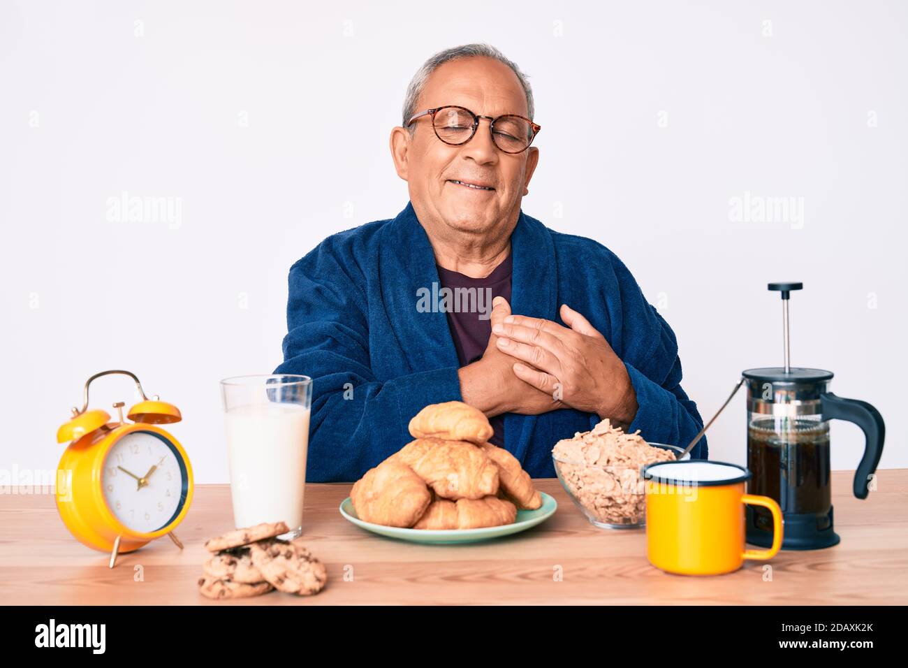 Senior handsome man with gray hair sitting on the table eating ...