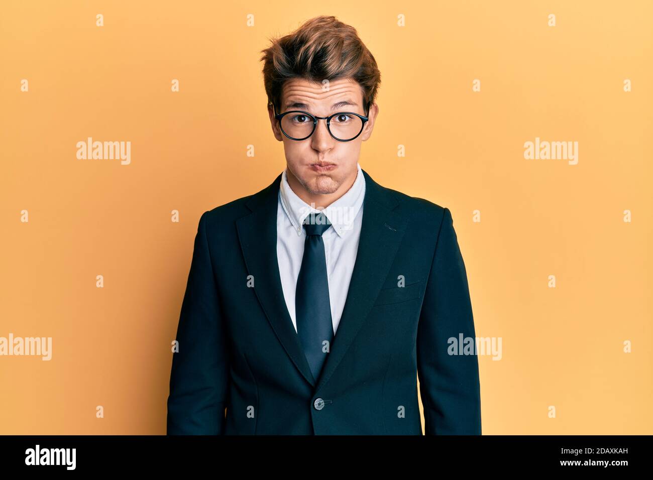 Handsome caucasian man wearing business suit and tie puffing cheeks ...