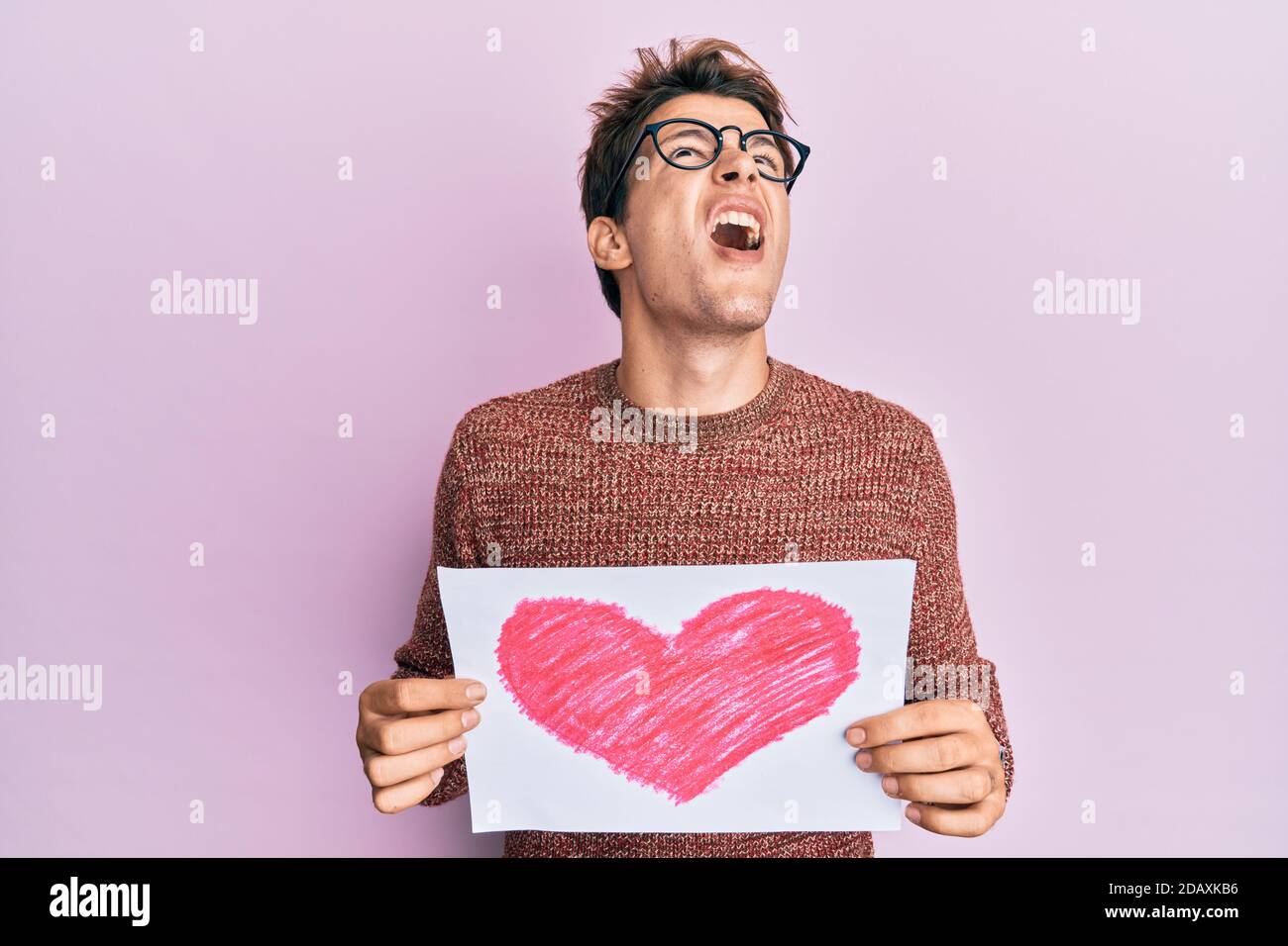 Handsome caucasian man holding heart draw angry and mad screaming ...