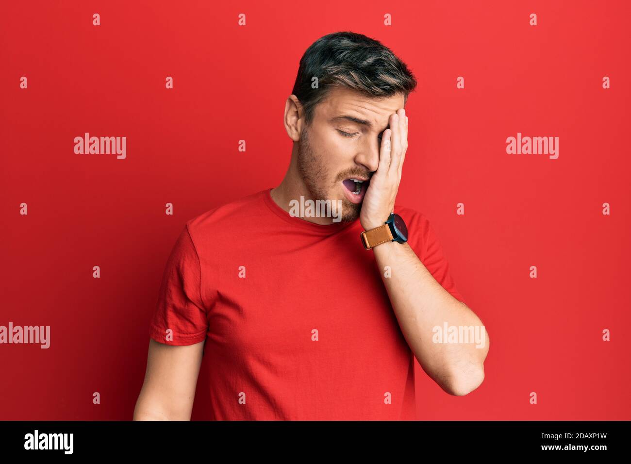 Handsome caucasian man wearing casual red tshirt yawning tired covering ...