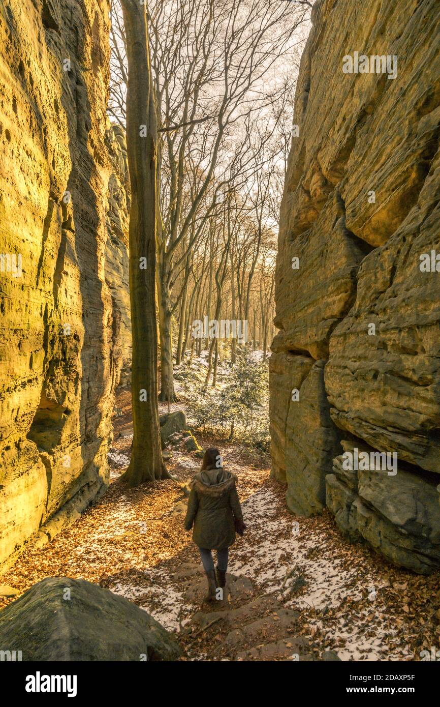 Single woman walking trough rock crevice in golden winter landscape ...