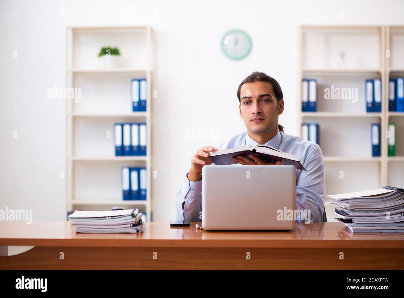 Young student employee reading book at workplace Stock Photo - Alamy
