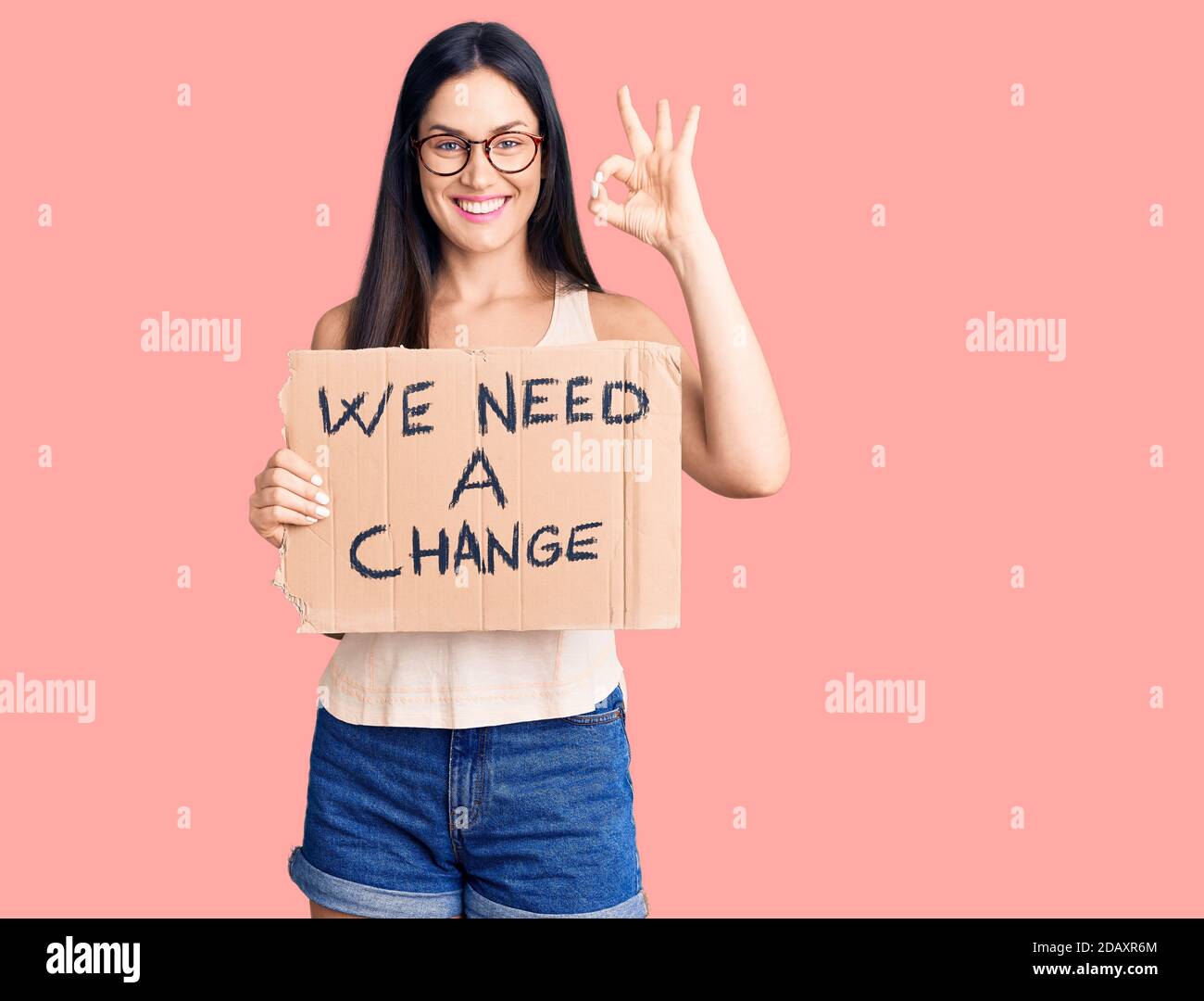 Young beautiful caucasian woman holding we need a change banner doing ...