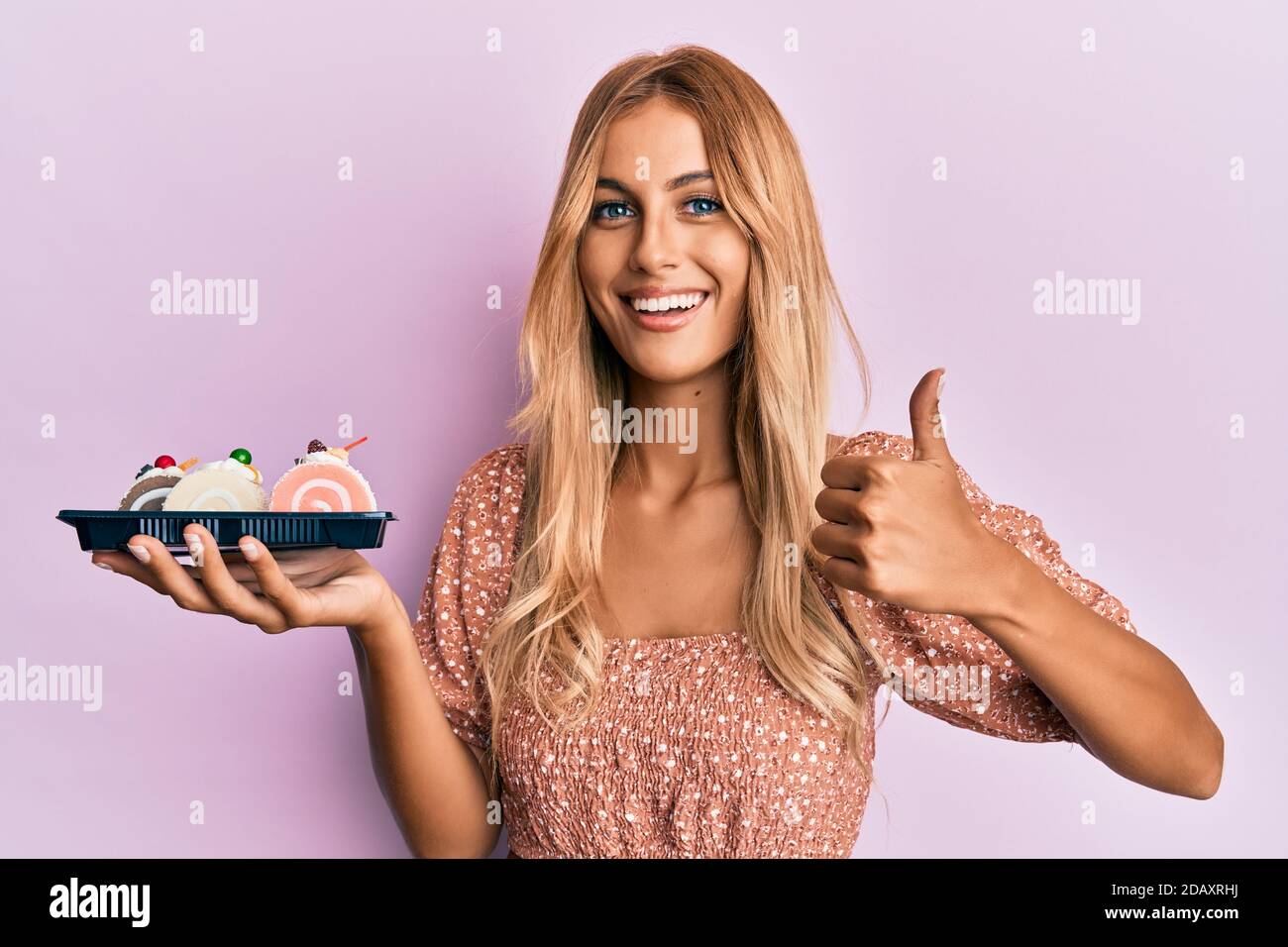 Beautiful blonde young woman holding cake sweets smiling happy and ...