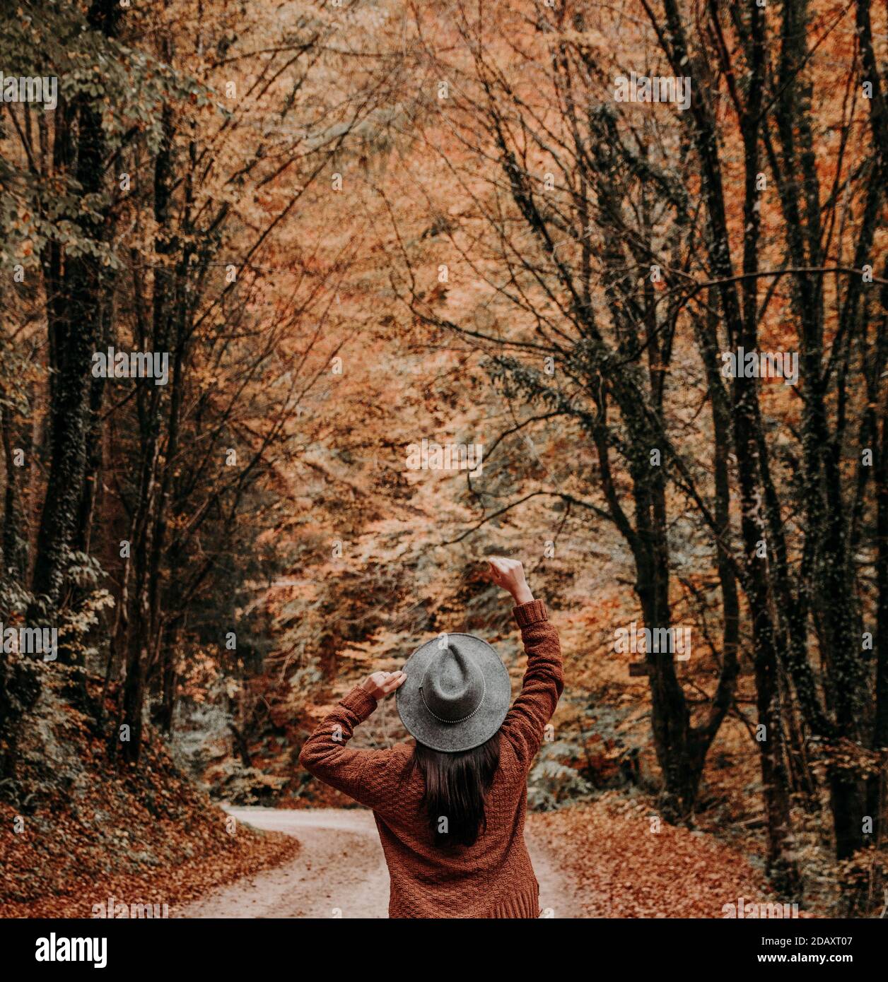 Female with open arms wearing a brown jacket with a fedora hat in a ...