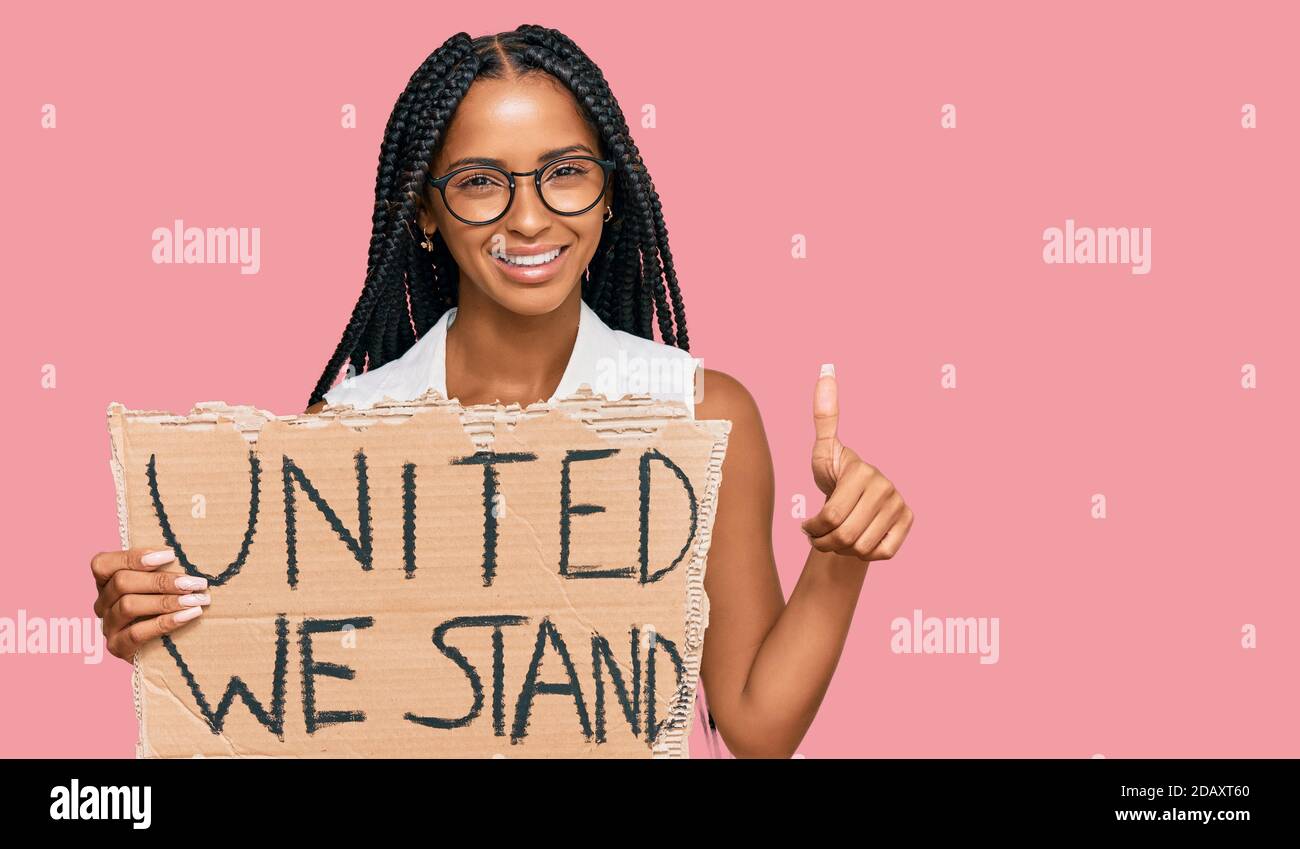 Beautiful hispanic woman holding united we stand banner smiling happy ...