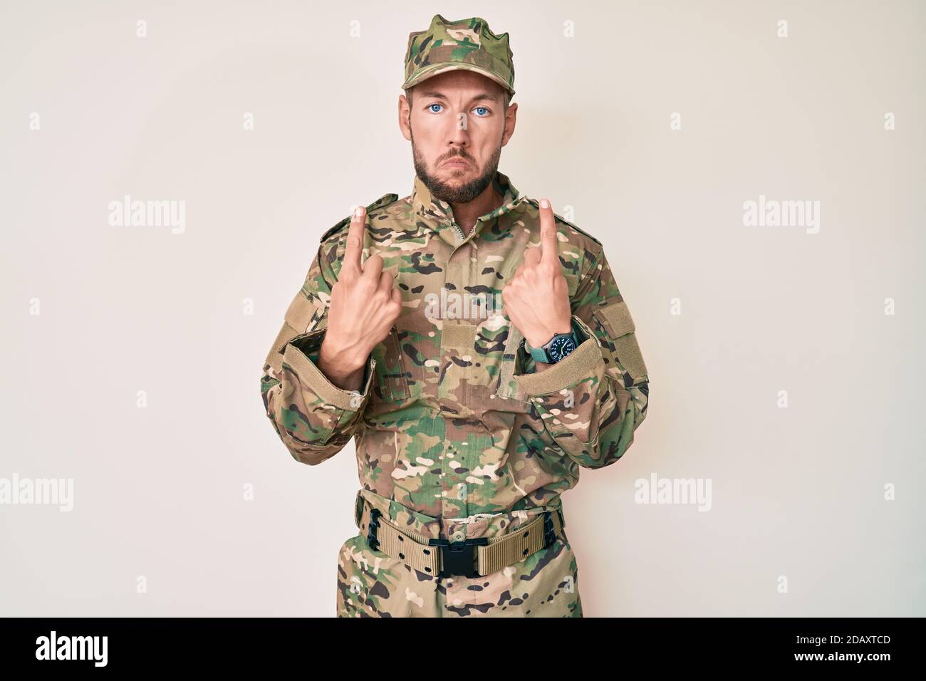 Young caucasian man wearing camouflage army uniform pointing up looking ...