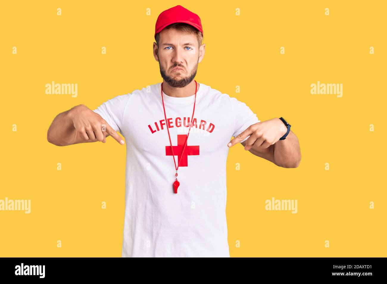 Young caucasian man wearing lifeguard t shirt holding whistle pointing ...