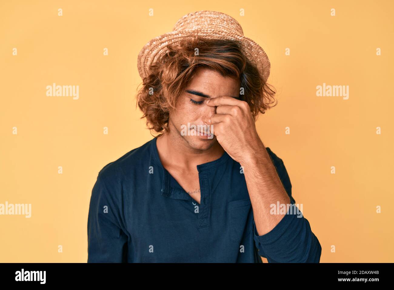 Young hispanic man wearing summer hat tired rubbing nose and eyes ...