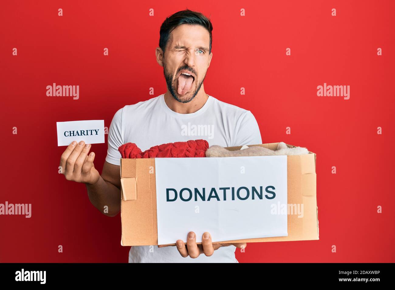 Young handsome man volunteer holding donations box with clothes ...
