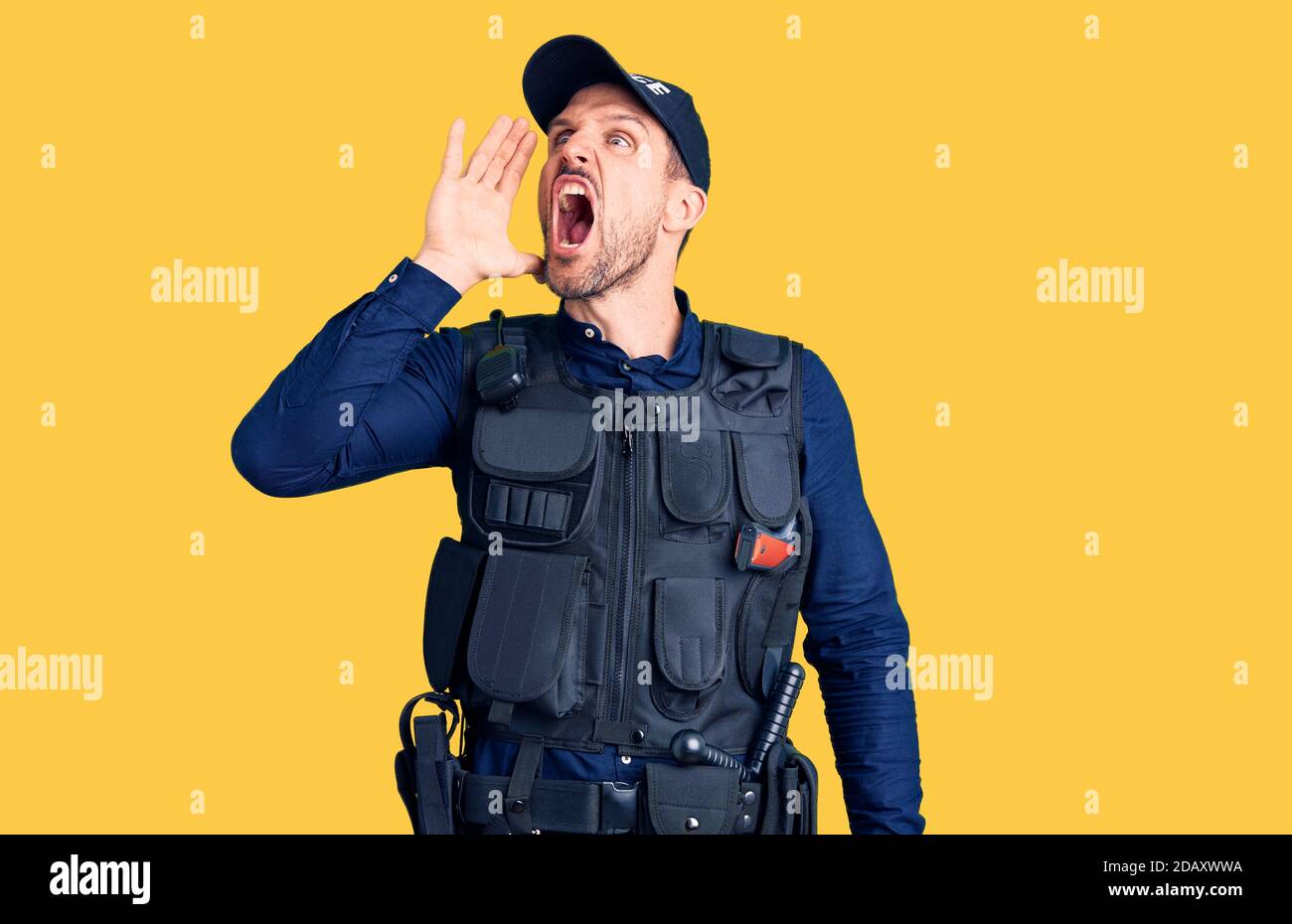 Young handsome man wearing police uniform shouting and screaming loud ...