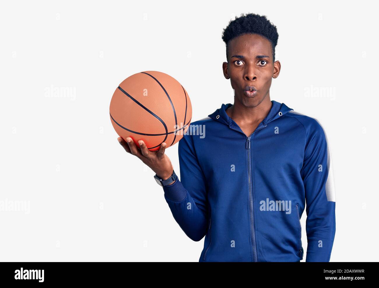 Young african american man holding basketball ball scared and amazed ...