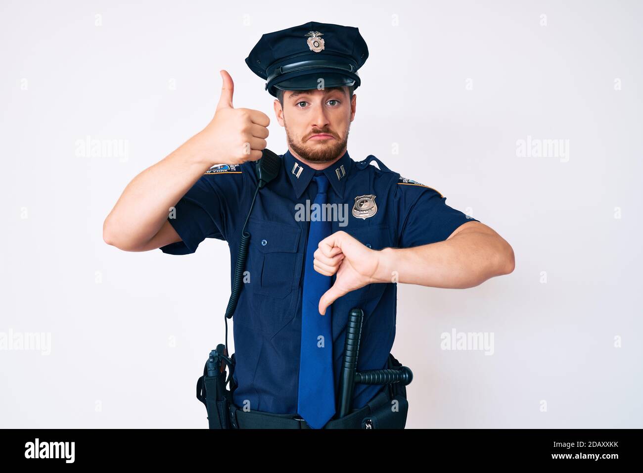 Young caucasian man wearing police uniform doing thumbs up and down ...