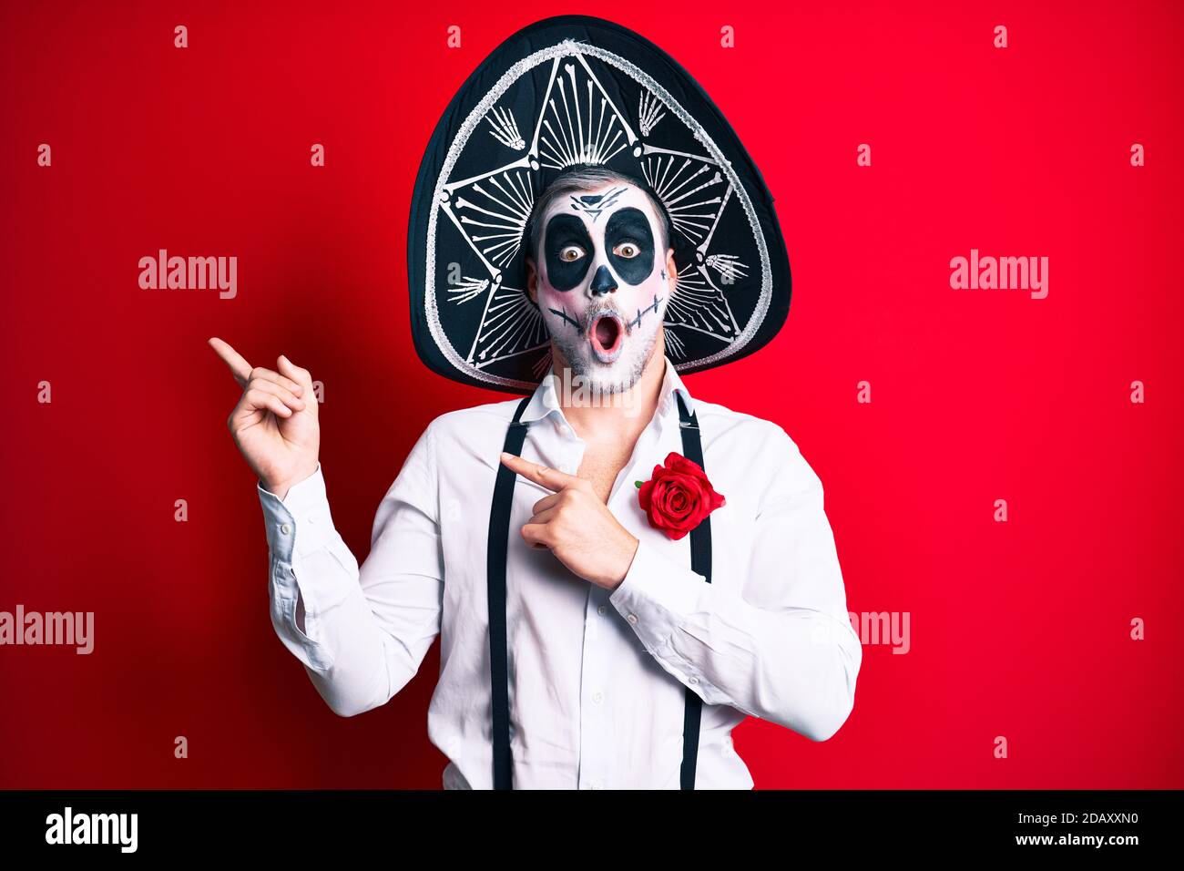Man wearing day of the dead costume pointing with fingers to the side ...