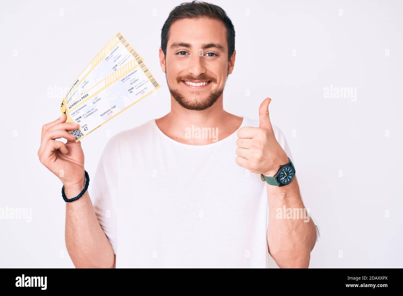Young handsome man holding boarding pass smiling happy and positive ...