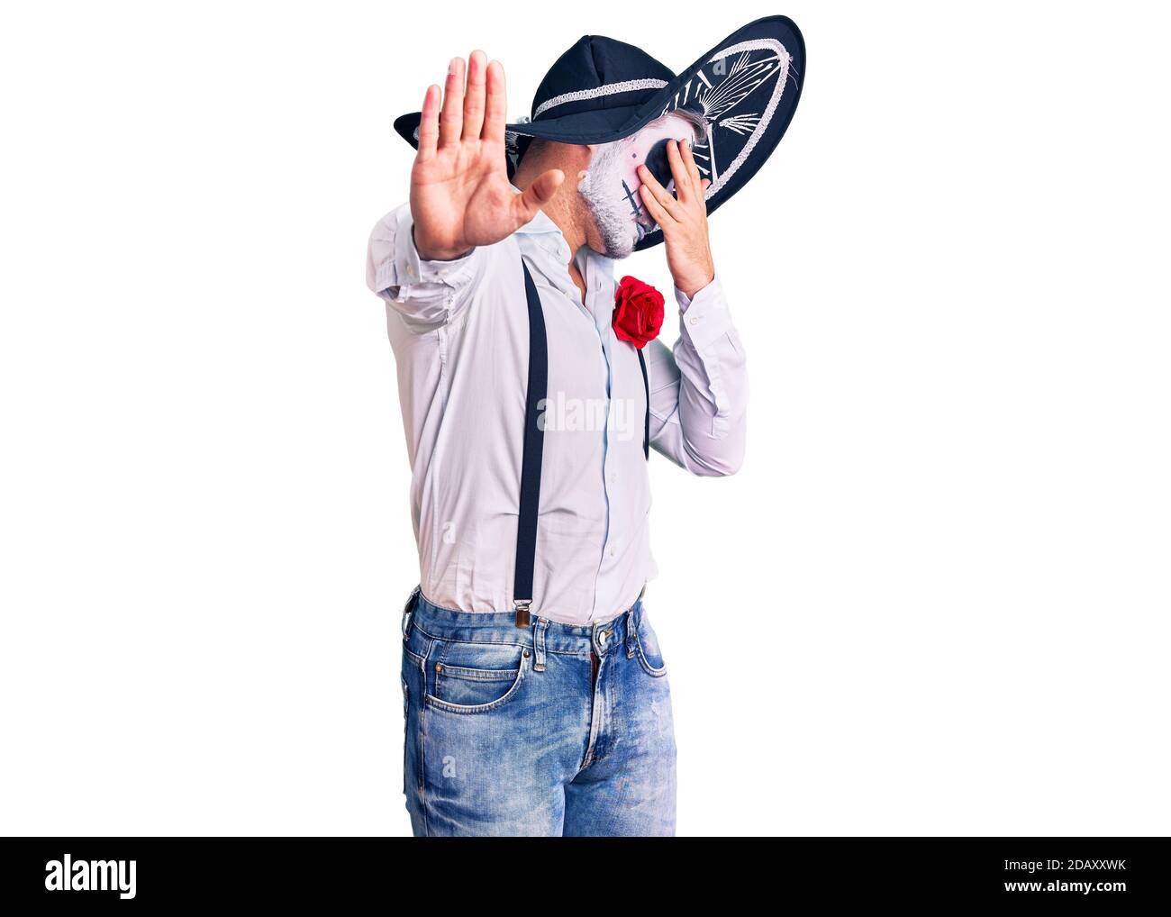 Man wearing day of the dead costume over background covering eyes with ...