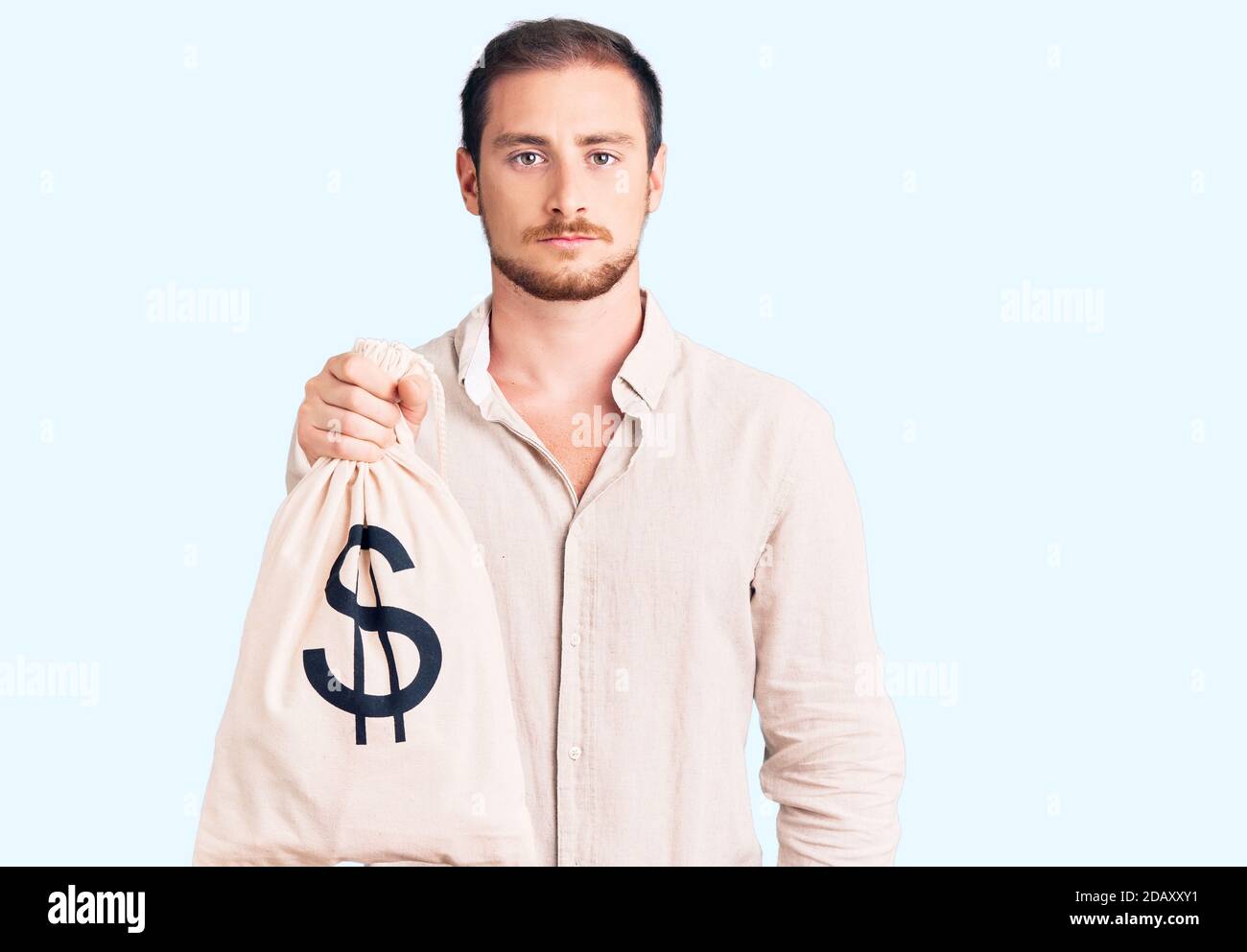 Young handsome caucasian man holding money bag with dollar symbol ...