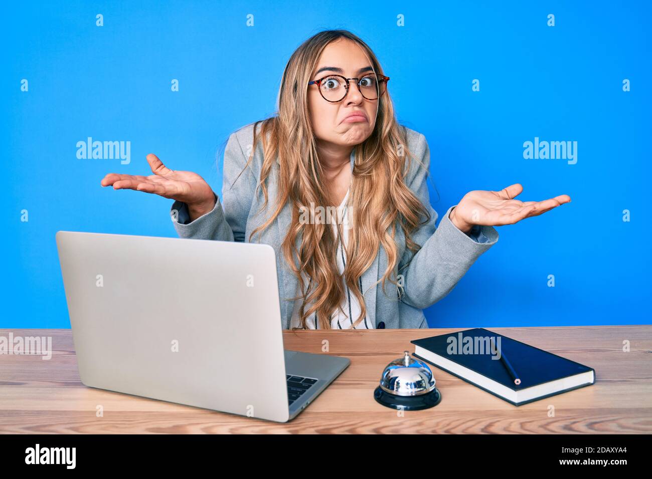 Young beautiful blonde woman sitting at hotel reception clueless and ...