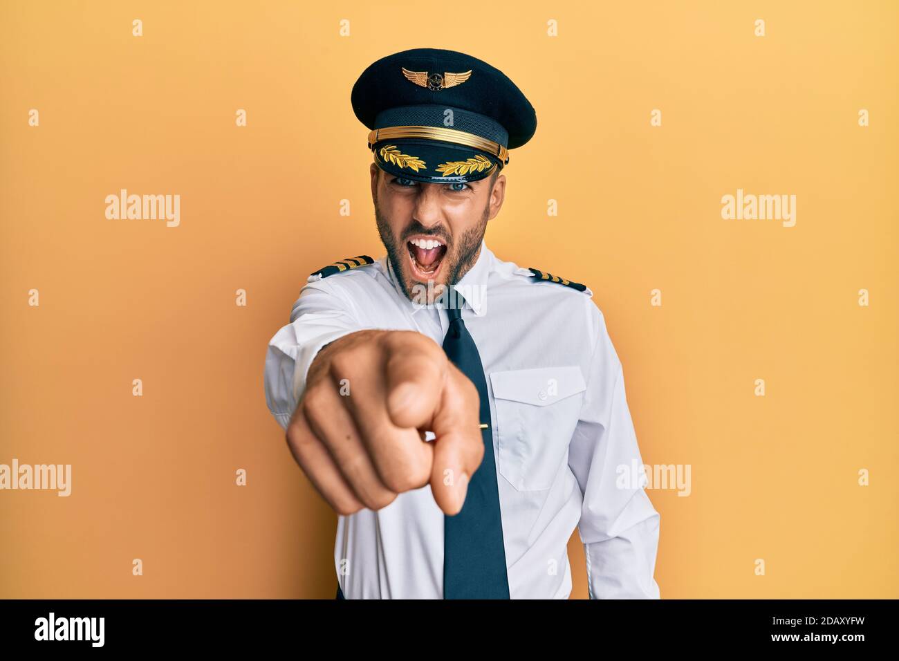 Handsome hispanic man wearing airplane pilot uniform pointing ...