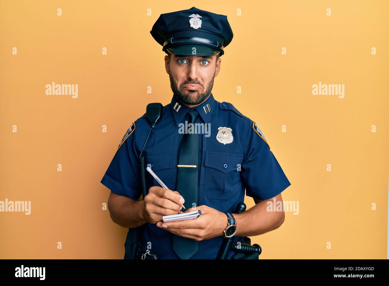 Handsome hispanic man wearing police uniform writing traffic fine ...