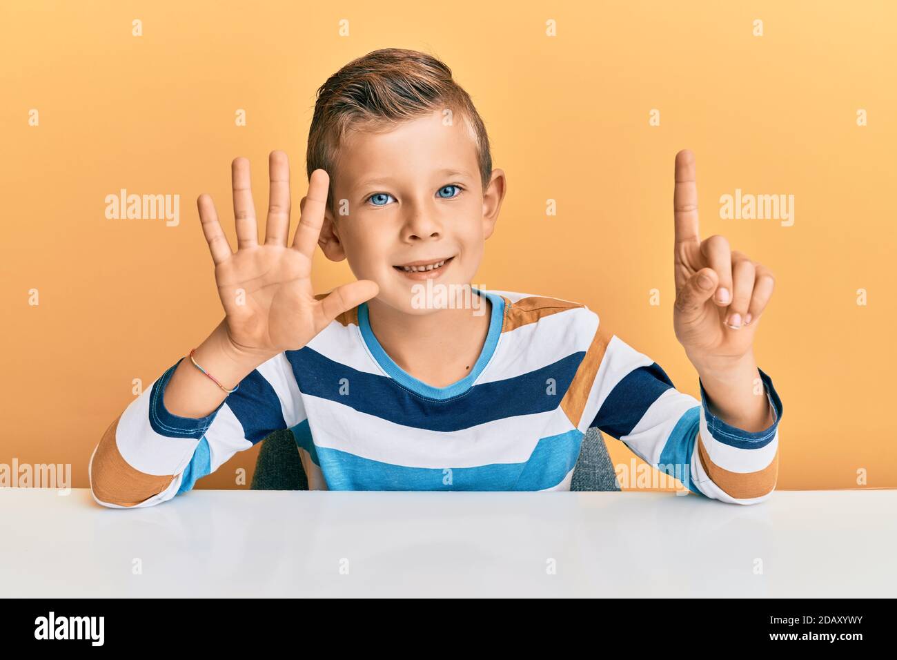 Adorable caucasian kid wearing casual clothes sitting on the table ...