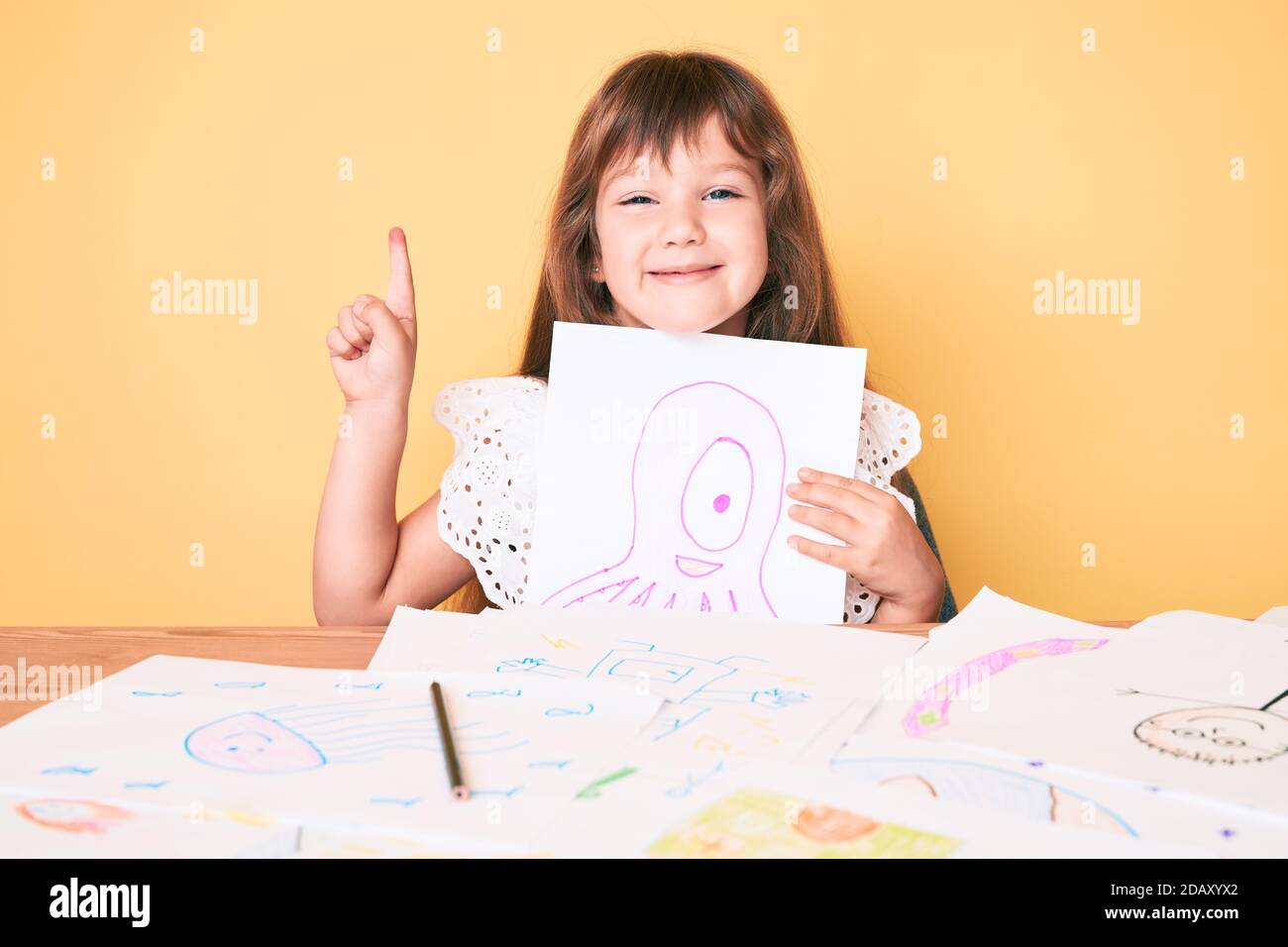 Little caucasian kid girl with long hair drawing colorful paintings ...