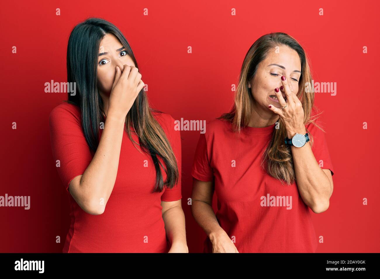 Hispanic family of mother and daughter wearing casual clothes over red ...
