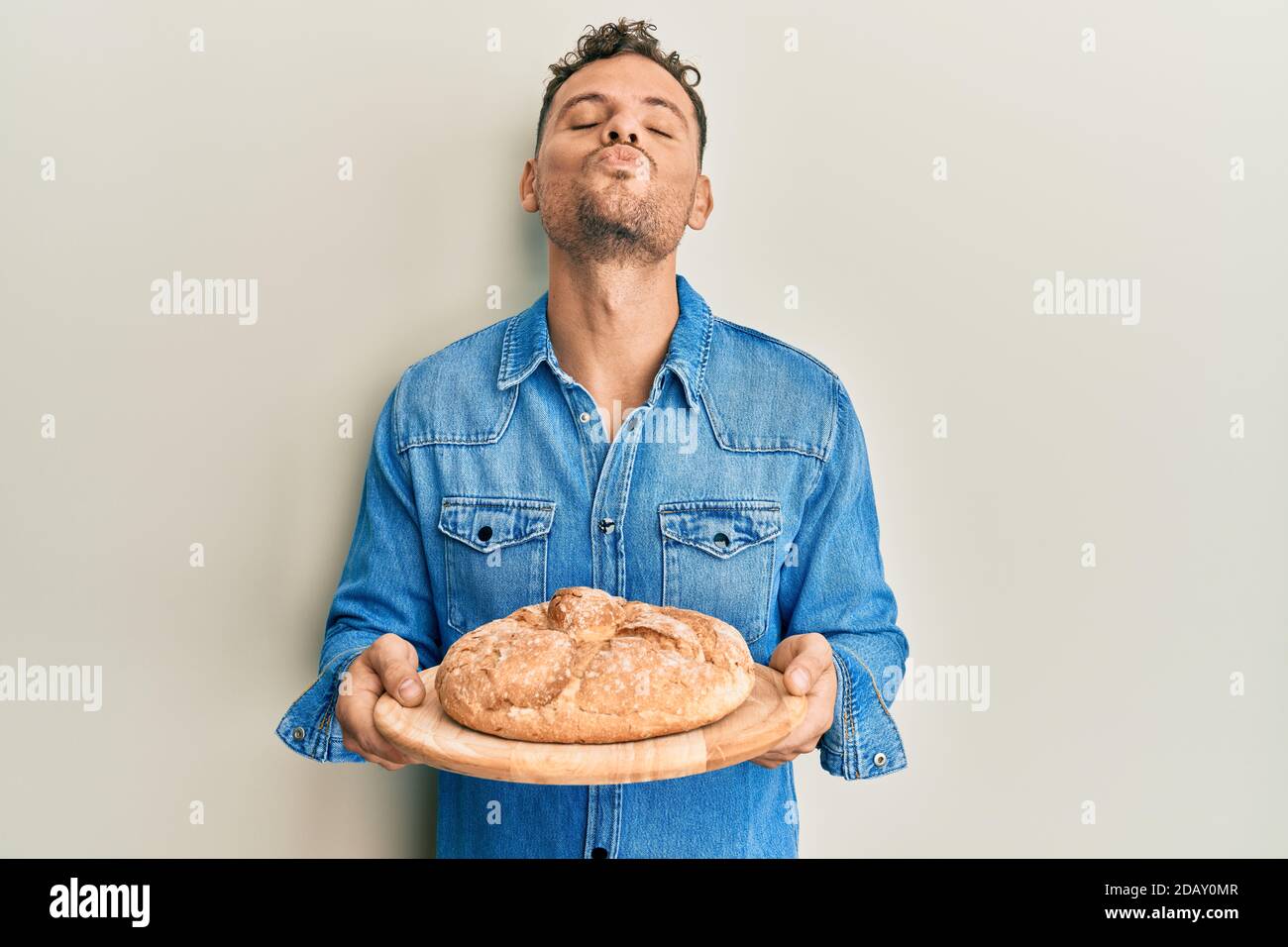 Handsome man with beard holding bread depressed and worry for distress ...