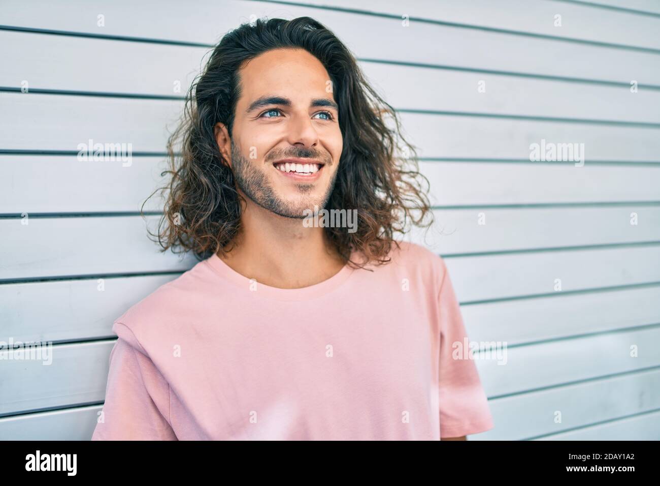 Young hispanic man smiling happy looking to the side leaning on the ...