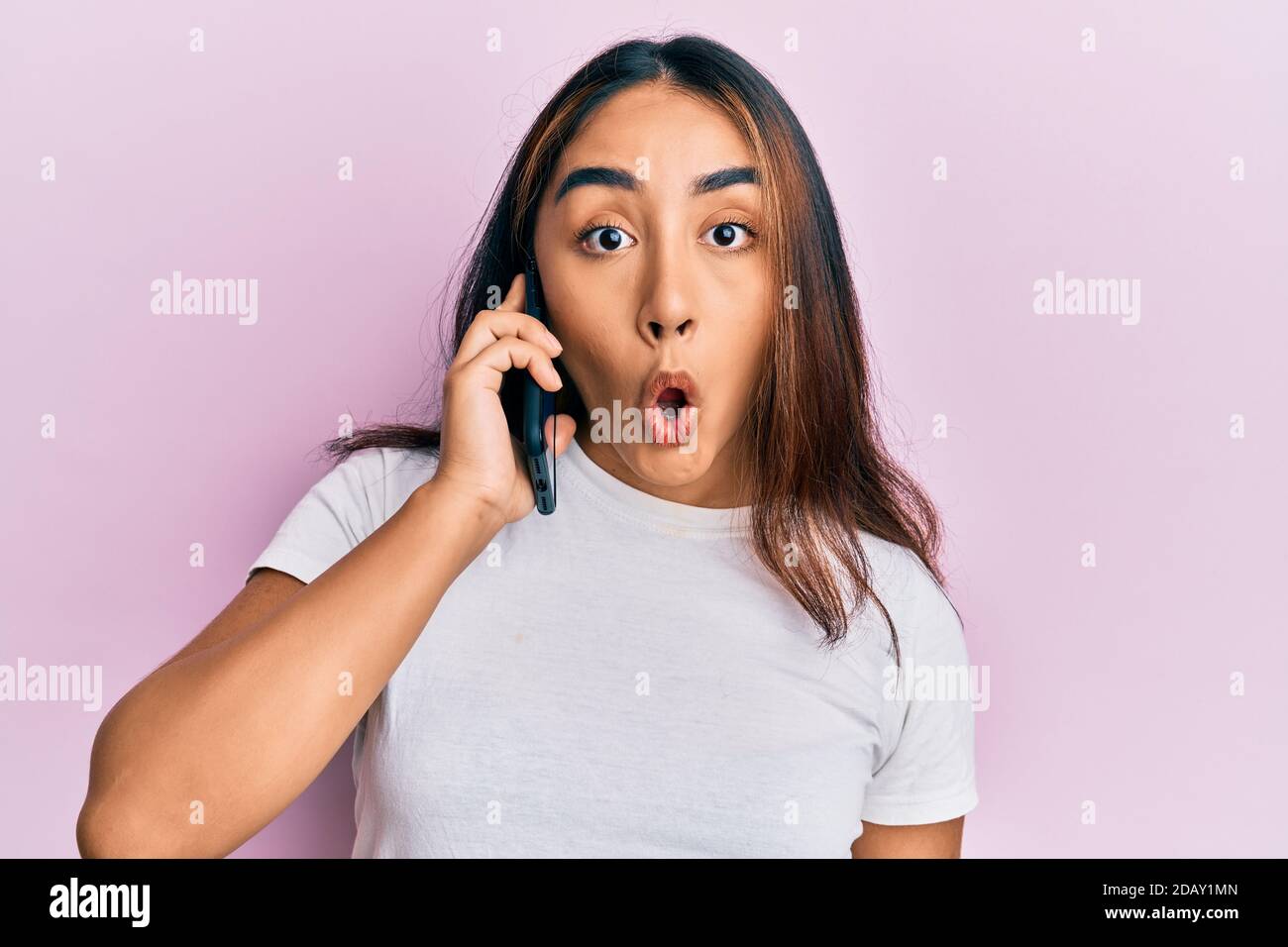 Young latin woman having conversation talking on the smartphone scared ...