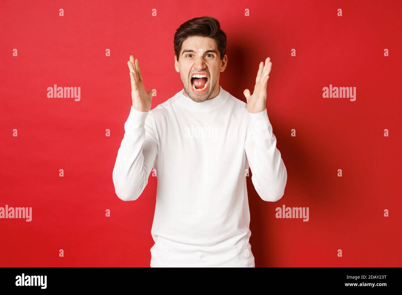 Image of frustrated and angry man in white sweater, shouting in rage ...