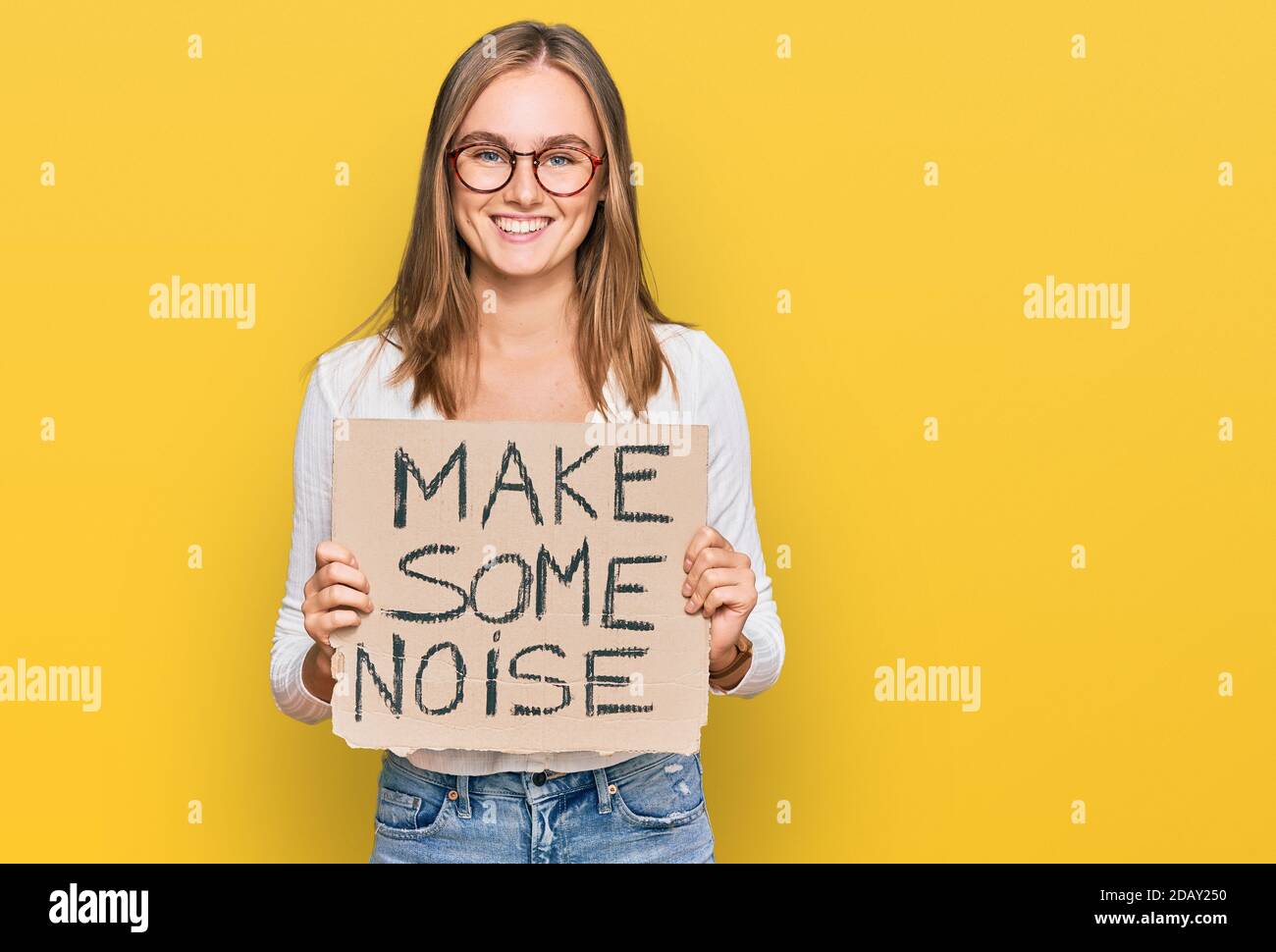 Beautiful blonde woman holding make some noise banner looking positive ...