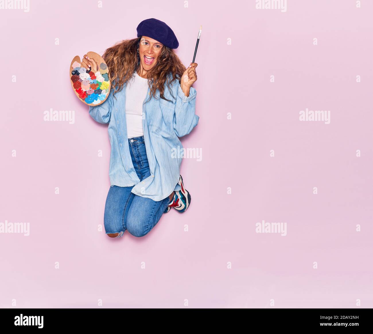 Young beautiful curly artist woman with tattoo wearing french beret ...