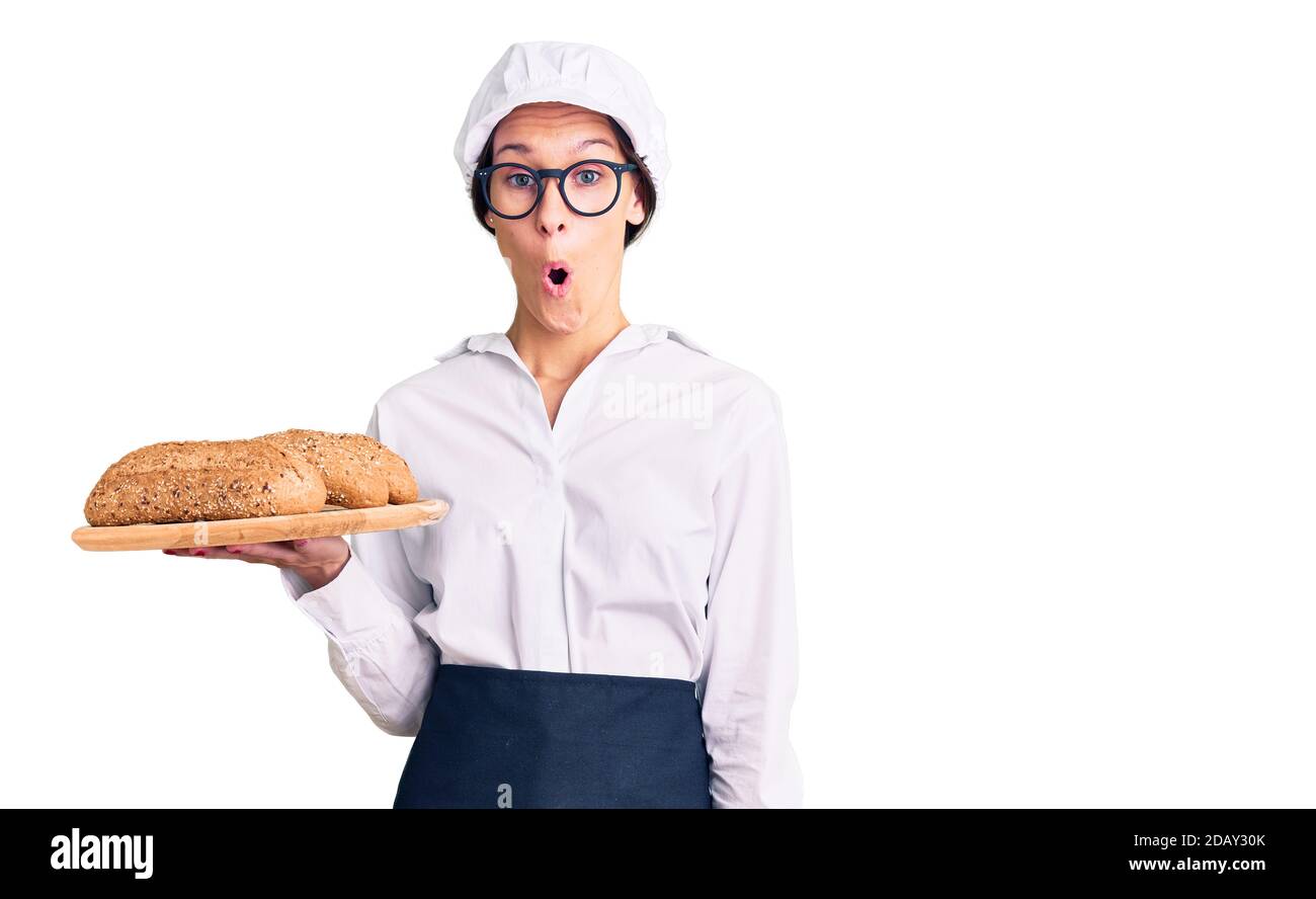 Beautiful brunette young woman wearing baker uniform holding homemade ...