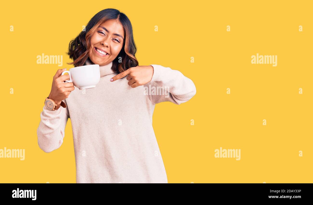 Young beautiful mixed race woman holding a cup of coffee smiling happy ...