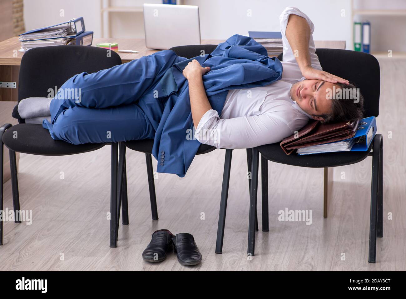 Young employee sleeping in the office on chairs Stock Photo - Alamy