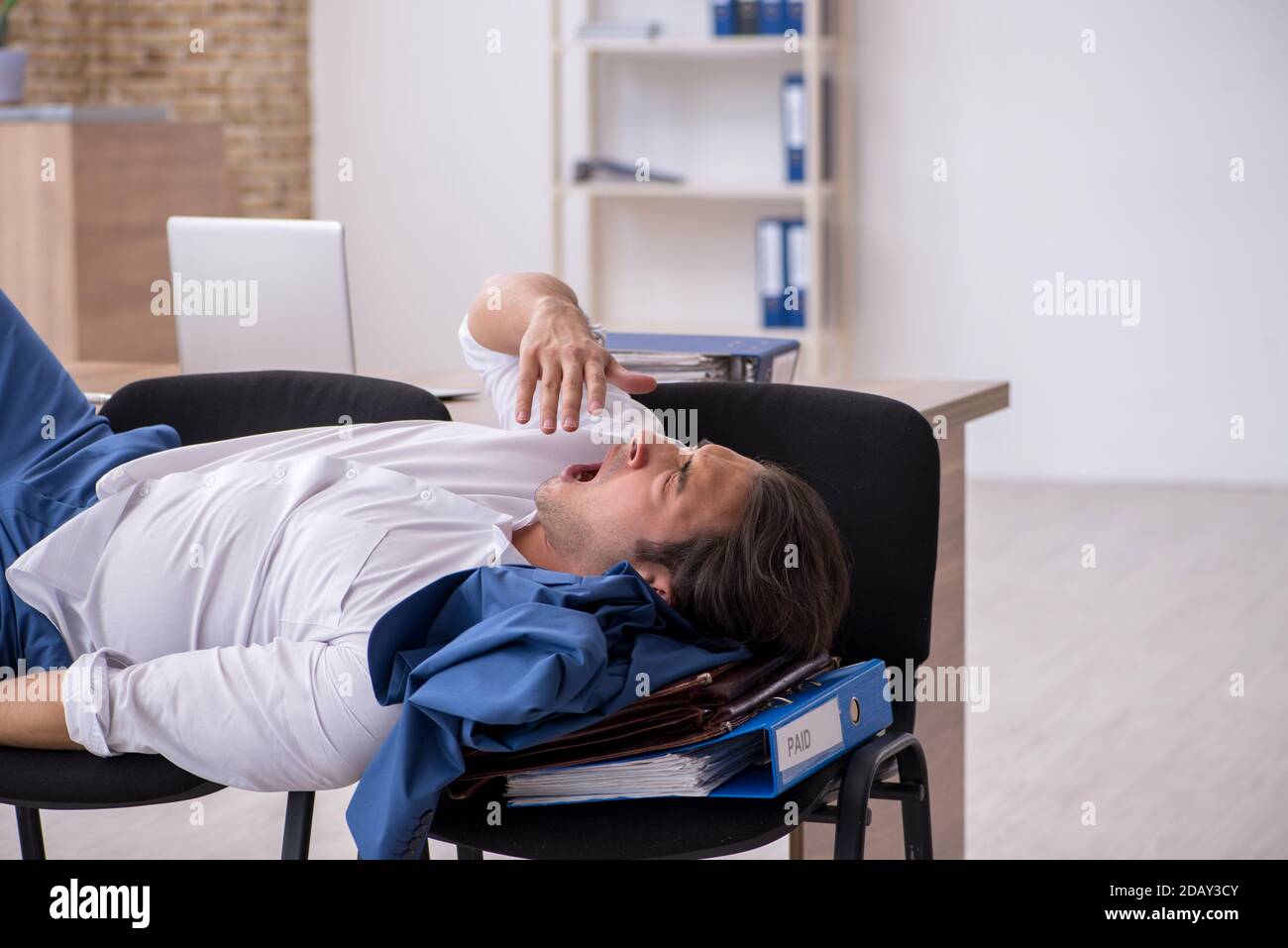 Young employee sleeping in the office on chairs Stock Photo - Alamy