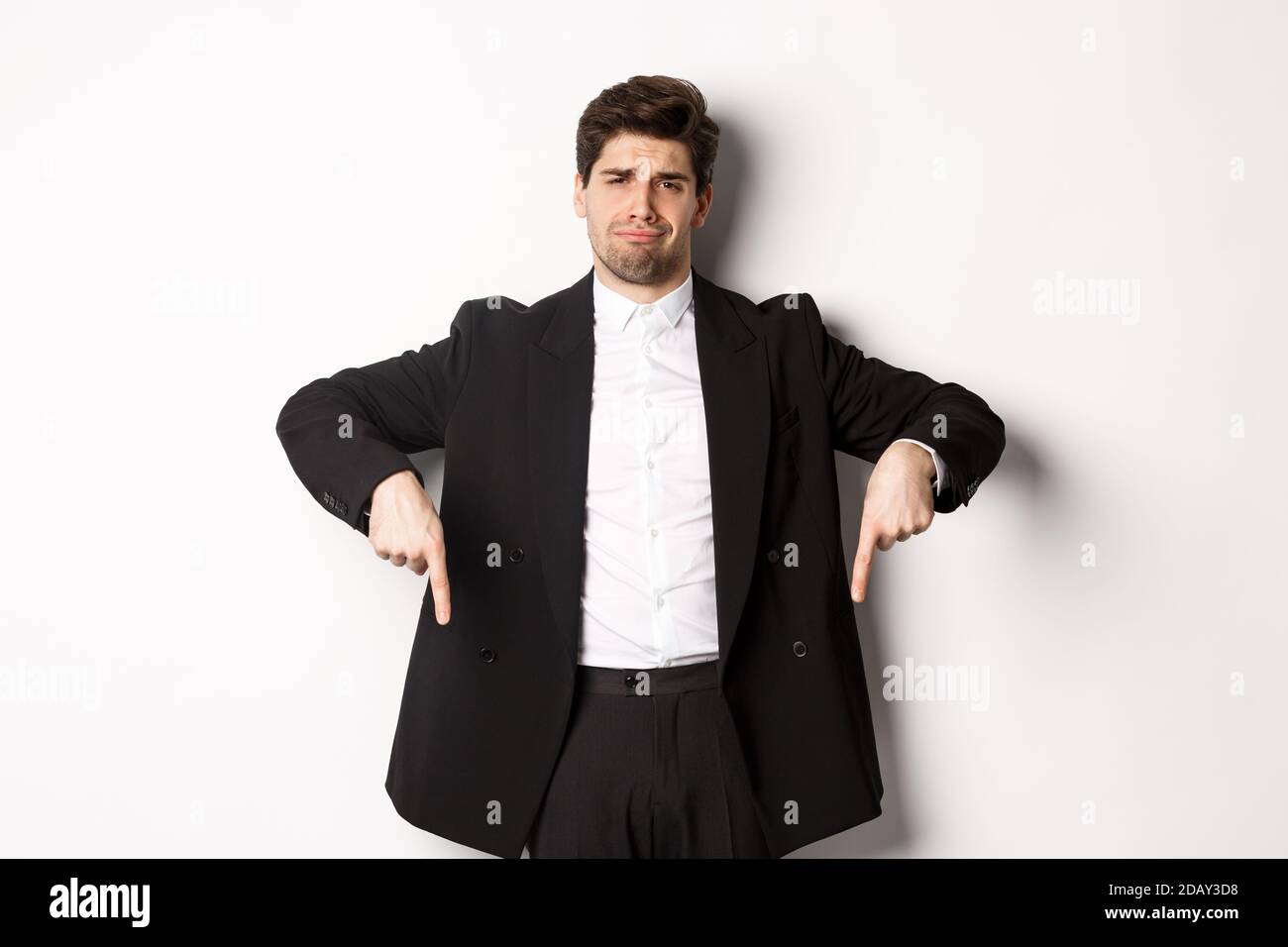 Portrait of skeptical and unamused bearded man, pointing fingers down ...