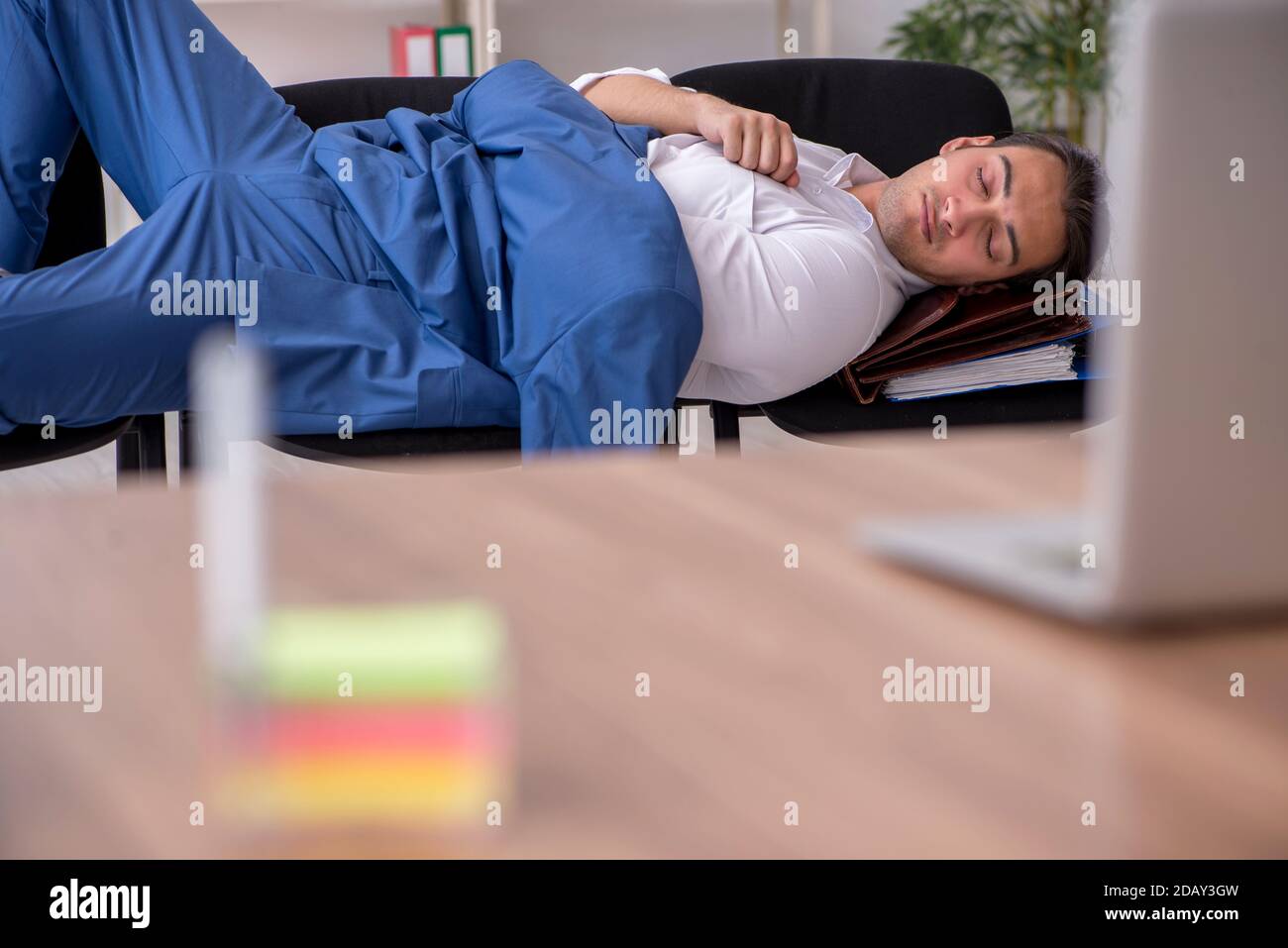 Young employee sleeping in the office on chairs Stock Photo - Alamy