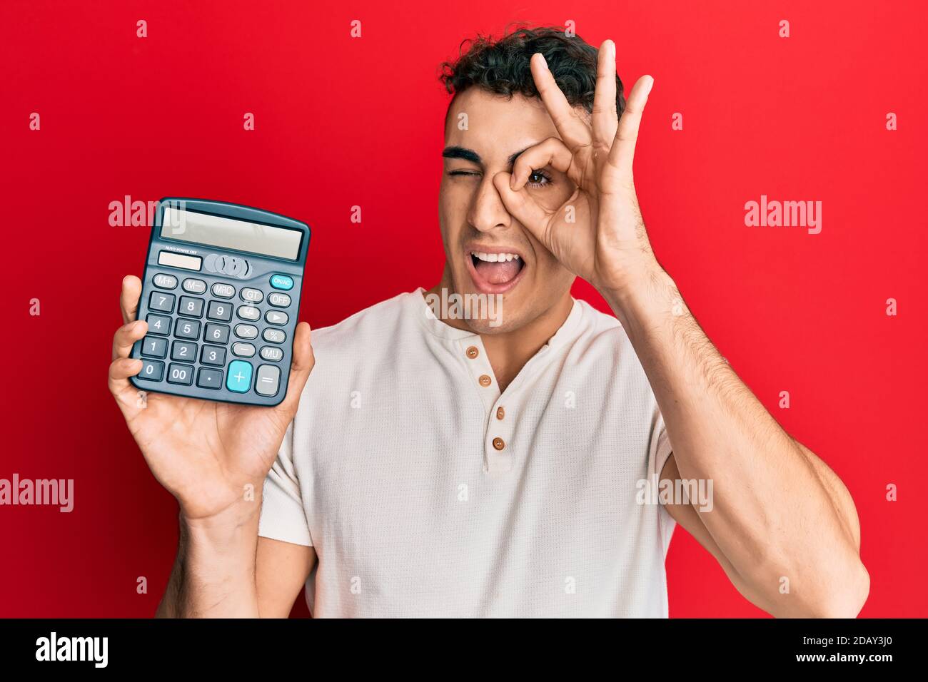 Handsome young man showing calculator device pointing thumb up to the ...