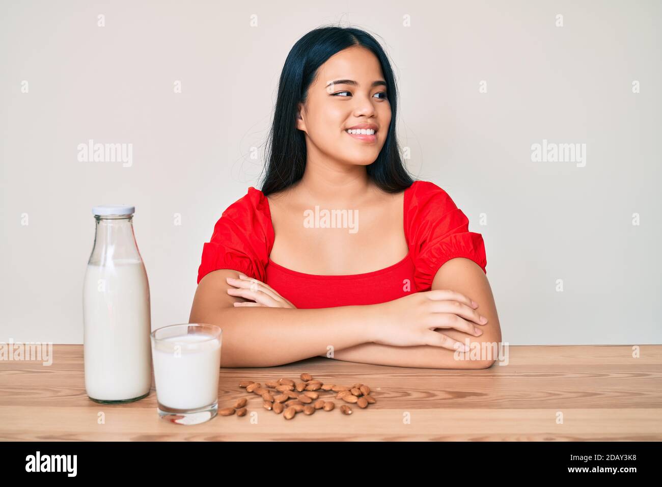 Young asian girl drinking healthy almond milk looking to side, relax ...