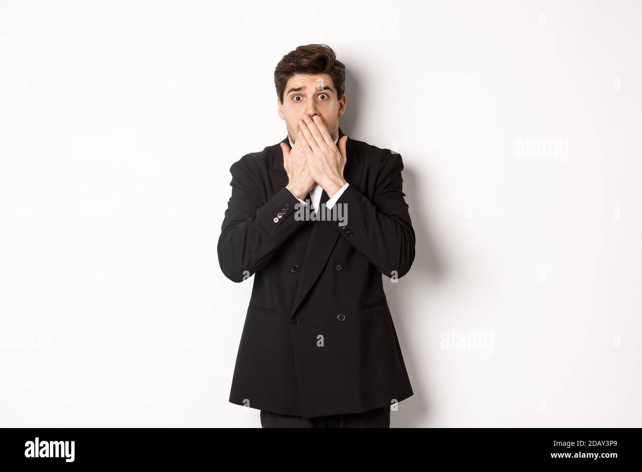 Scared man in formal suit, gasping and looking frightened at camera ...