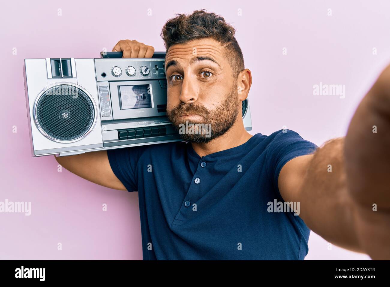 Handsome man with beard holding boombox, listening to music puffing ...