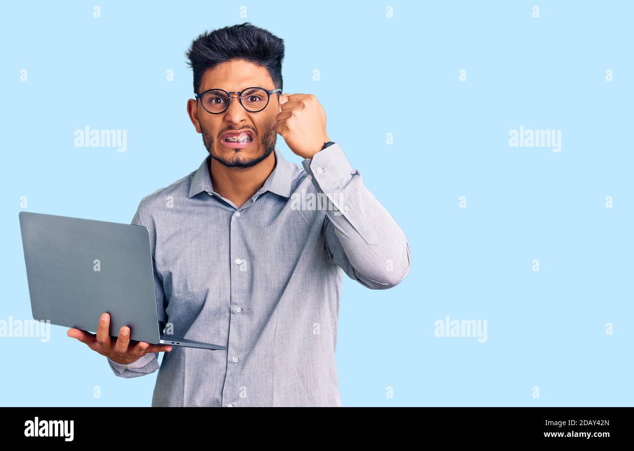 Handsome latin american young man working using computer laptop annoyed ...