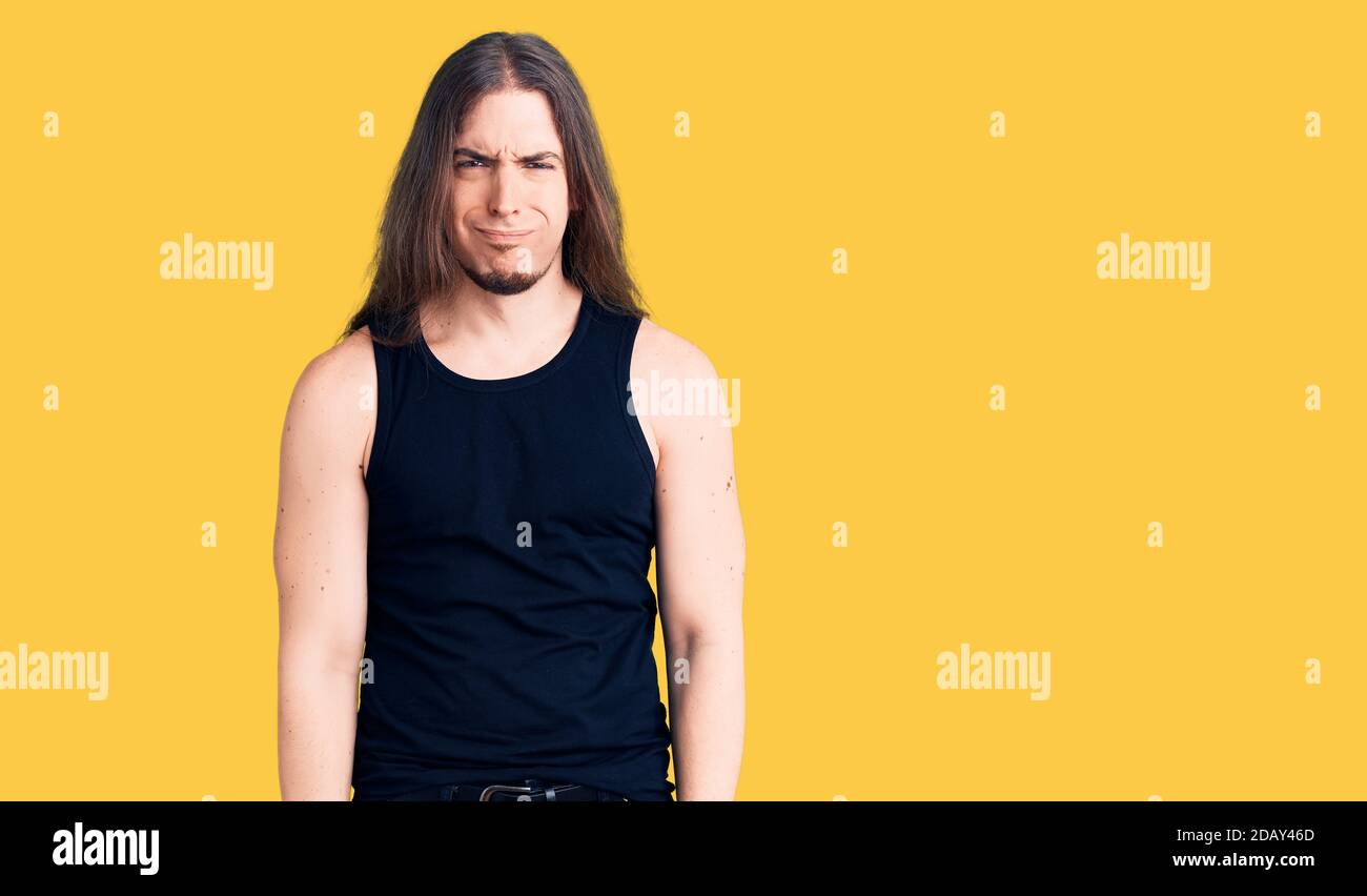 Young adult man with long hair wearing goth style with black clothes ...