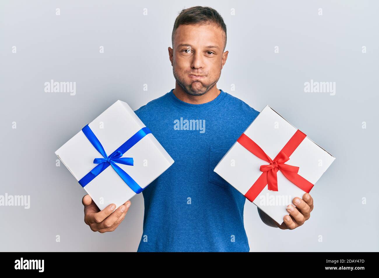 Handsome muscle man holding gifts puffing cheeks with funny face. mouth ...