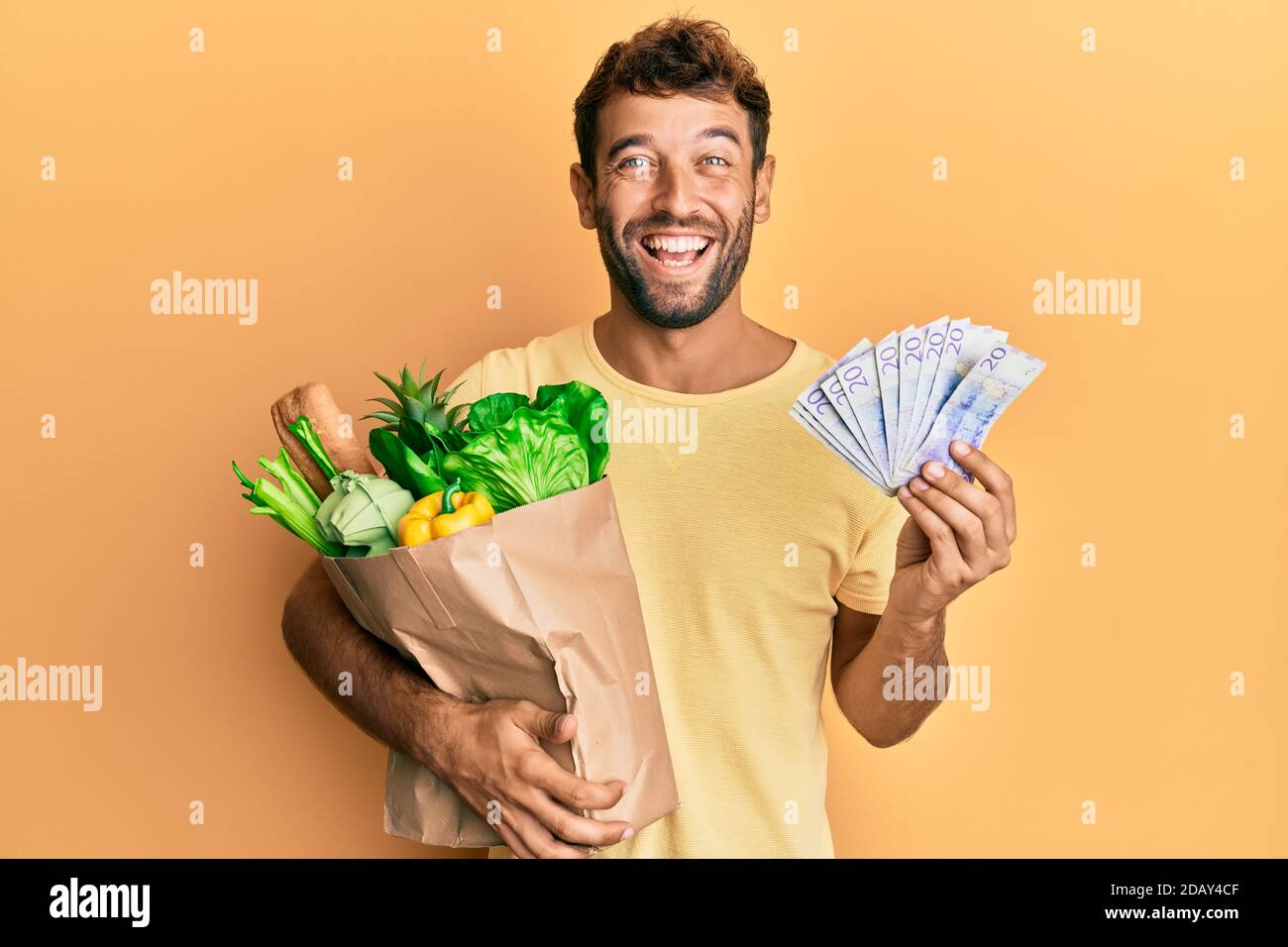 Handsome man with beard holding groceries and 20 swedish krona ...