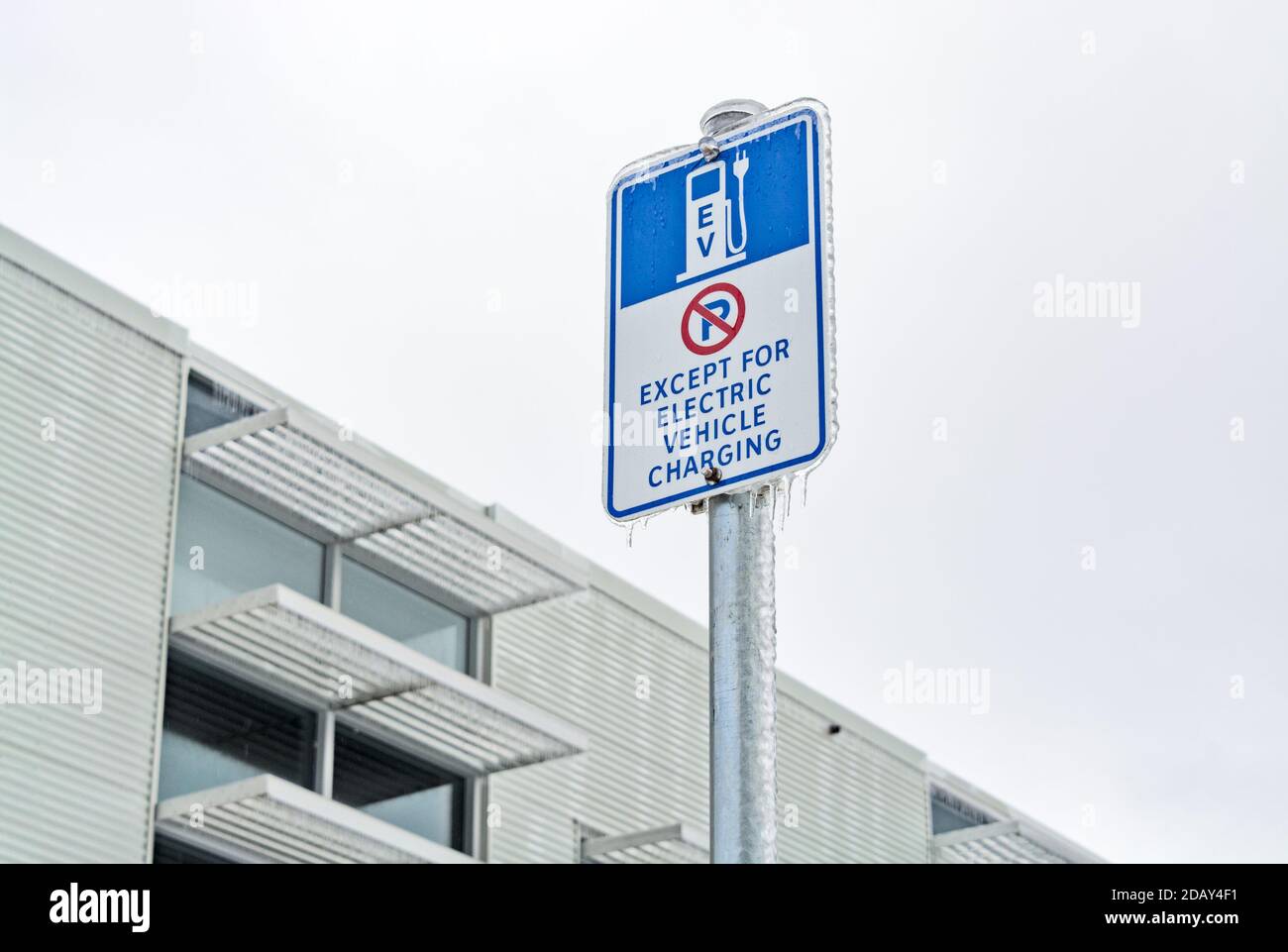 EV charging station sign in icicles and office building on the ...