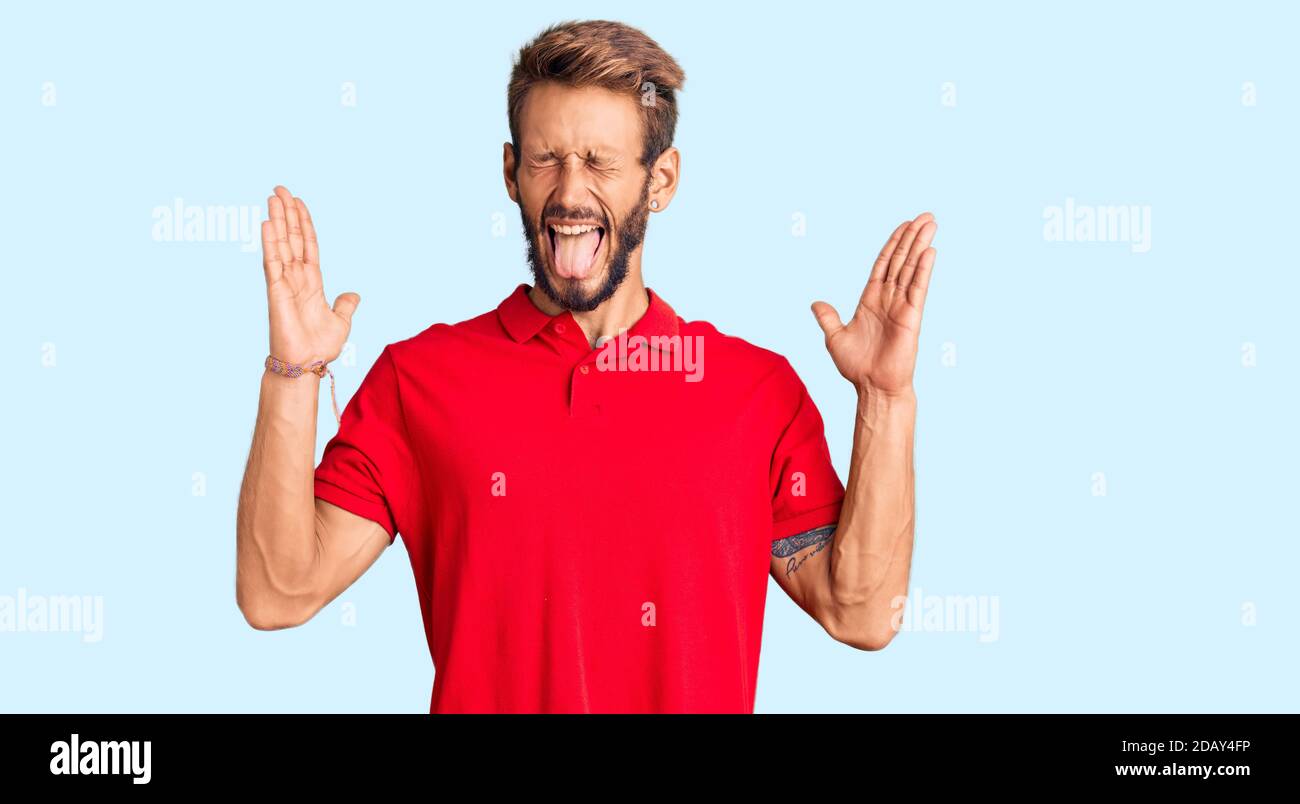 Handsome blond man with beard wearing casual clothes celebrating mad ...